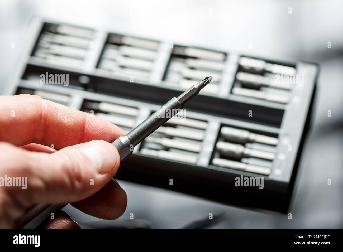 Hand holding screwdriver with chanchable metal bit. Houshold ...