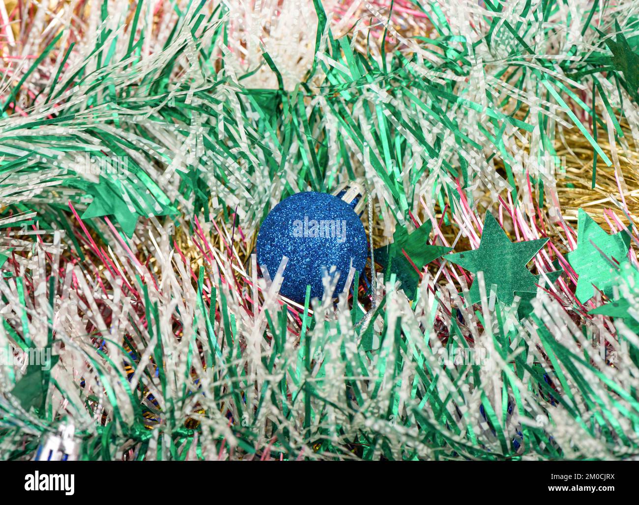 Close-up of a blue Christmas toy ball among New Year's tinsel. Abstract ...