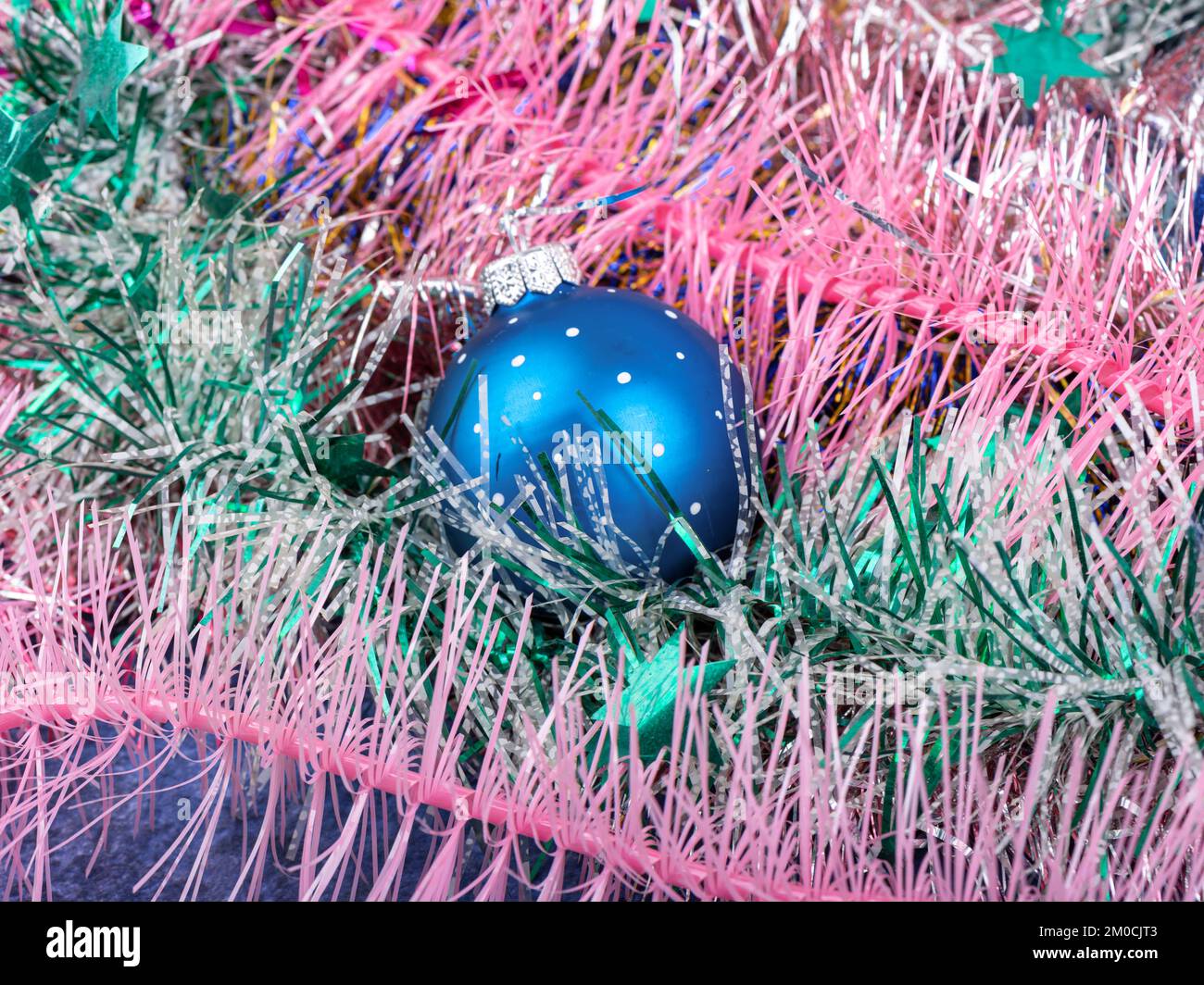 Blue Christmas toy ball among New Year's tinsel. Abstract background or ...