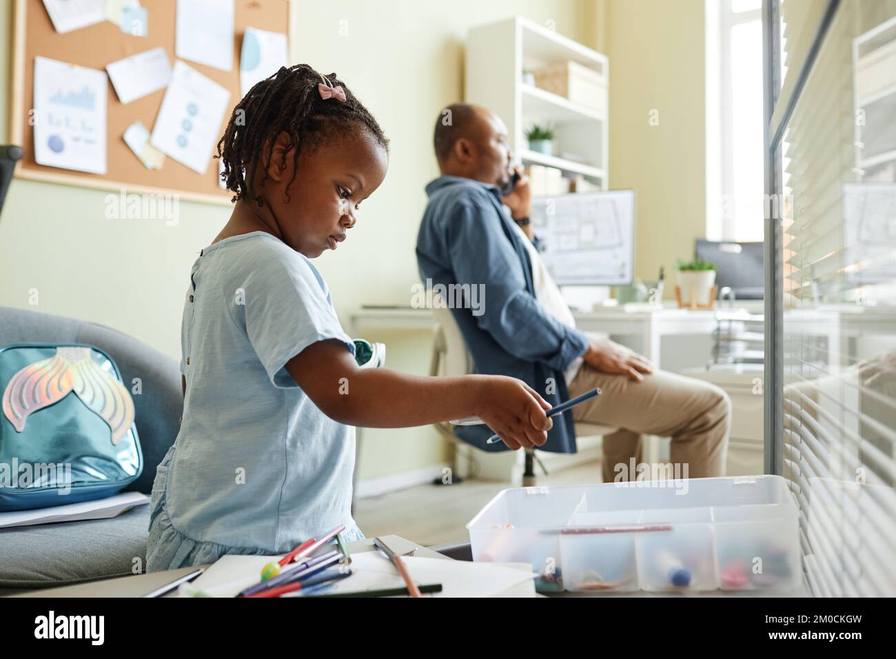 Side view portrait of black little girl choosing colored pencils while ...