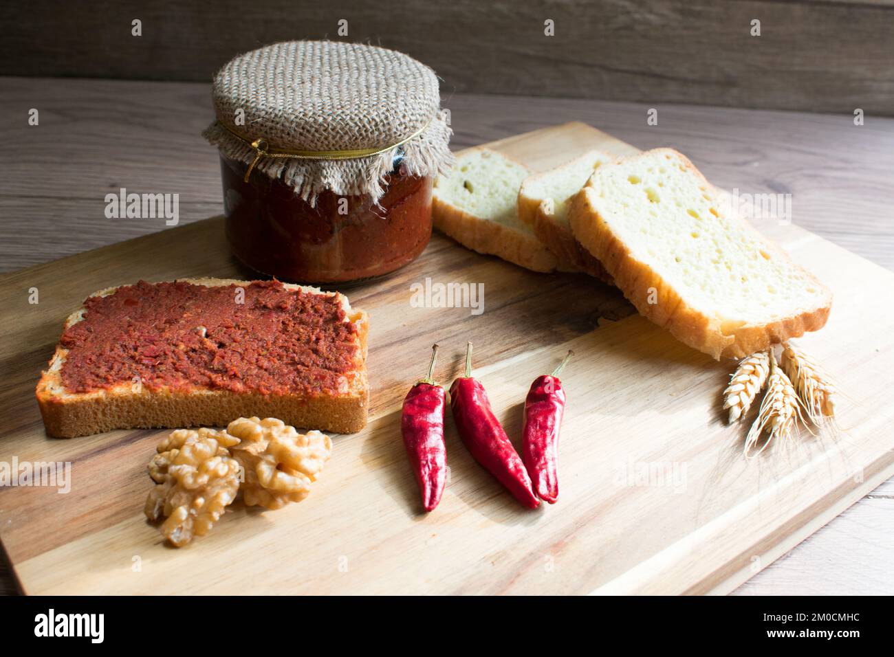 Pepper paste in jar and slice of bread with pepper paste on wooden ...