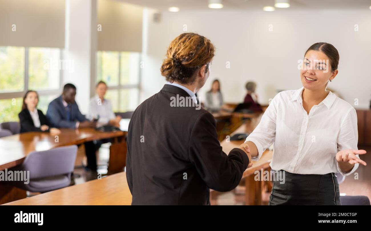Middle aged white male manager welcoming a new white female employee ...