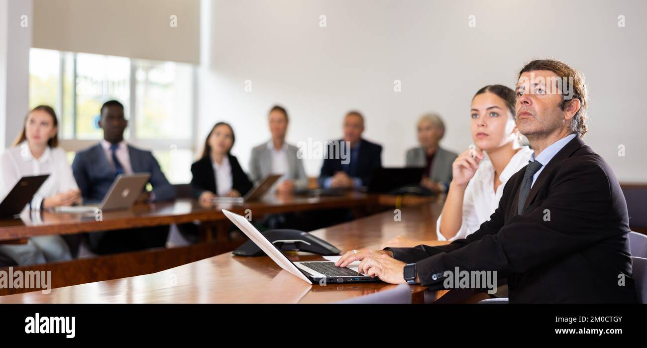 Group of employees attentively listening to business presentation in ...