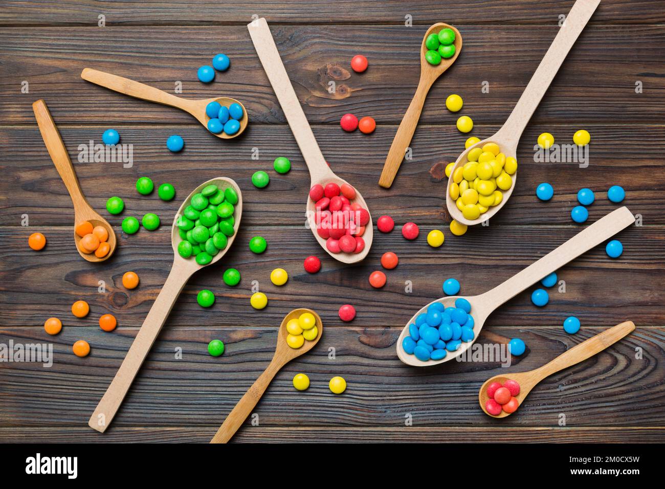 delicious colorful sweet candies on spoon on colored background ...