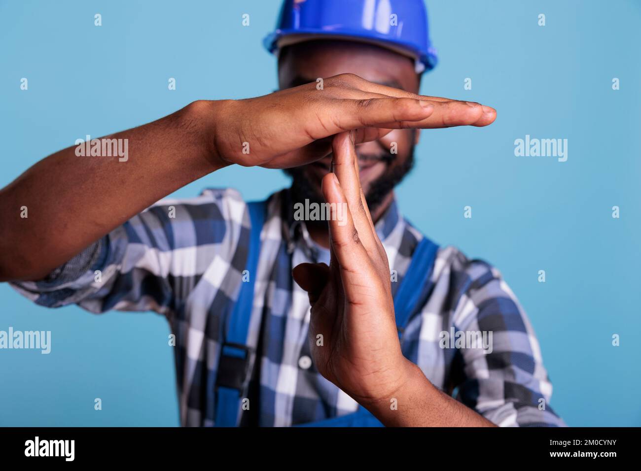 Smiling builder making the gesture of waiting time and pause in the ...