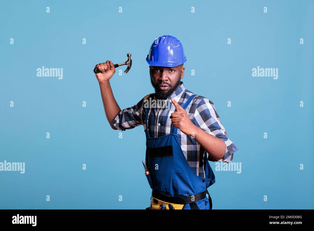 Aggressive and disruptive construction worker raising hammer towards ...