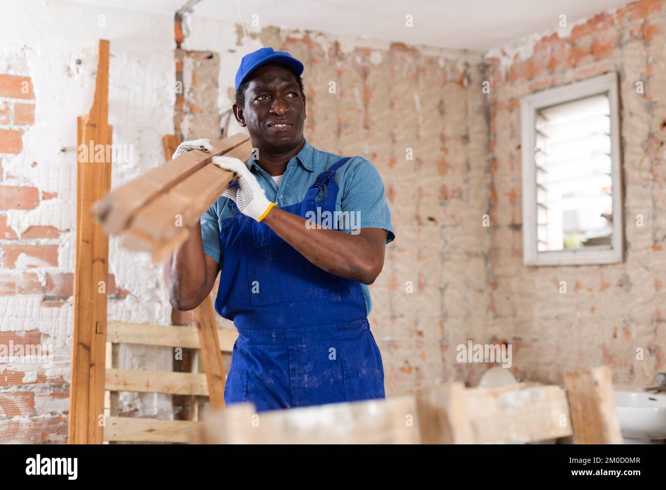 African american builder arranging timber in building under renovation ...