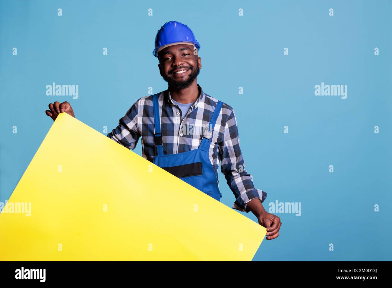 Relaxed construction worker with protective helmet presenting a panel ...