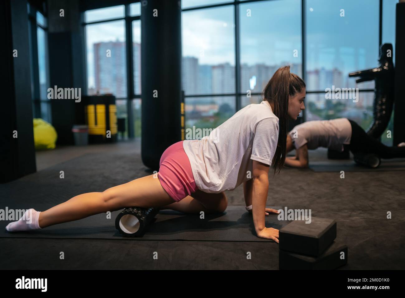 Young woman using a foam roller while doing stretching exercises Stock ...