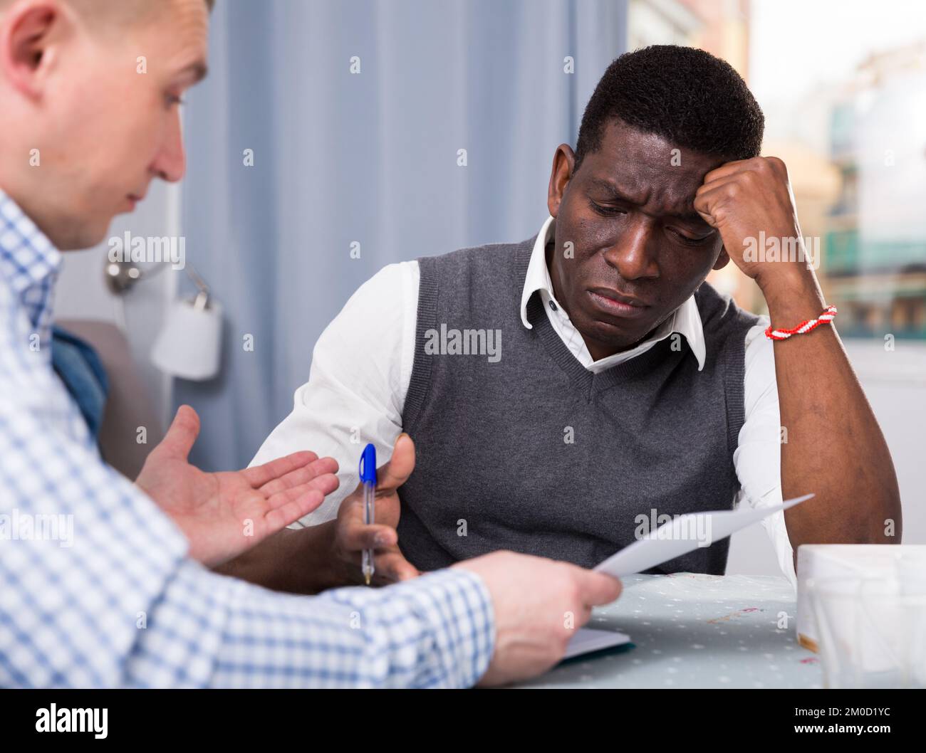 Upset man with friend looking worriedly at papers at home Stock Photo ...