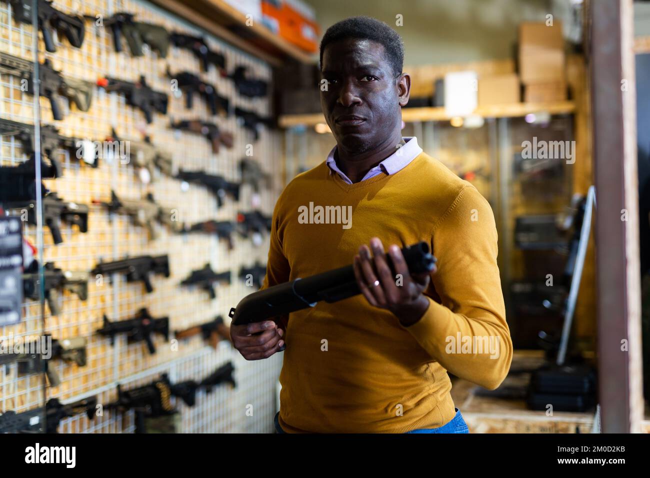 African american man chooses pump-action shotgun in gun store closeup ...