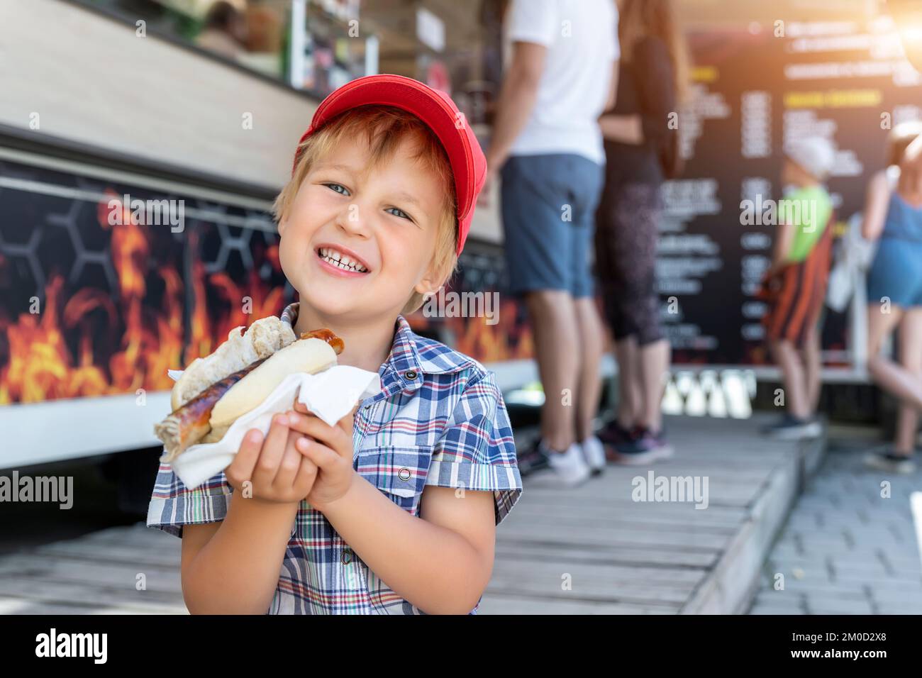 Cute adorable little happy smiling boy kid enjoy eating hot dog sausage ...