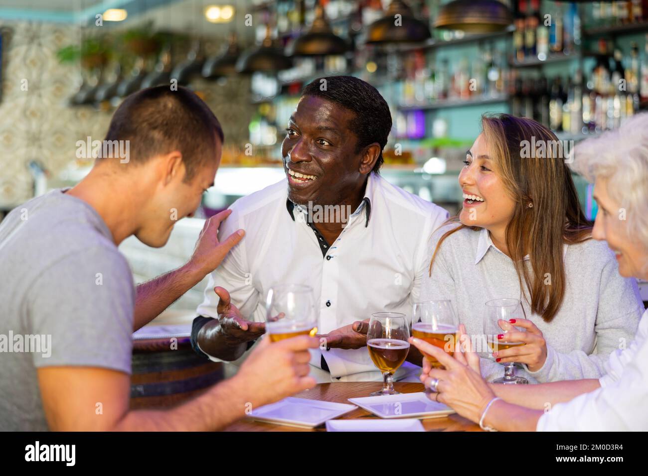 Happy diverse people drinking beer and eating tapas while spending time ...