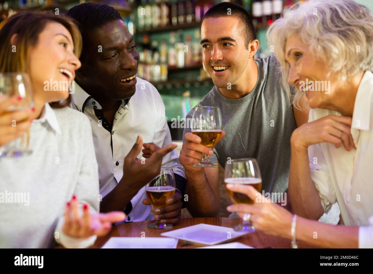 Happy diverse people drinking beer and eating tapas while spending time ...