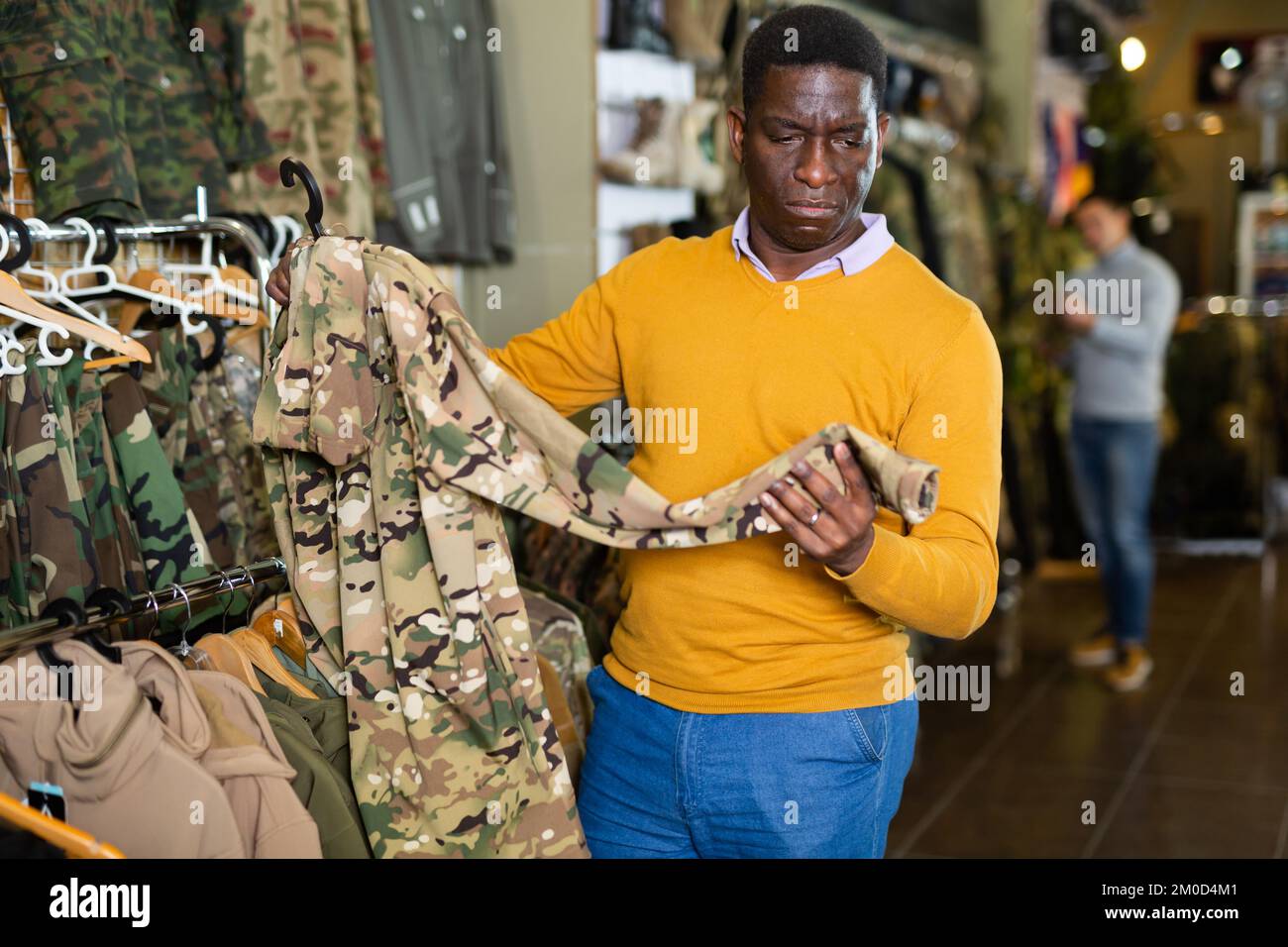 Male shopper chooses camouflage uniform at army store Stock Photo - Alamy