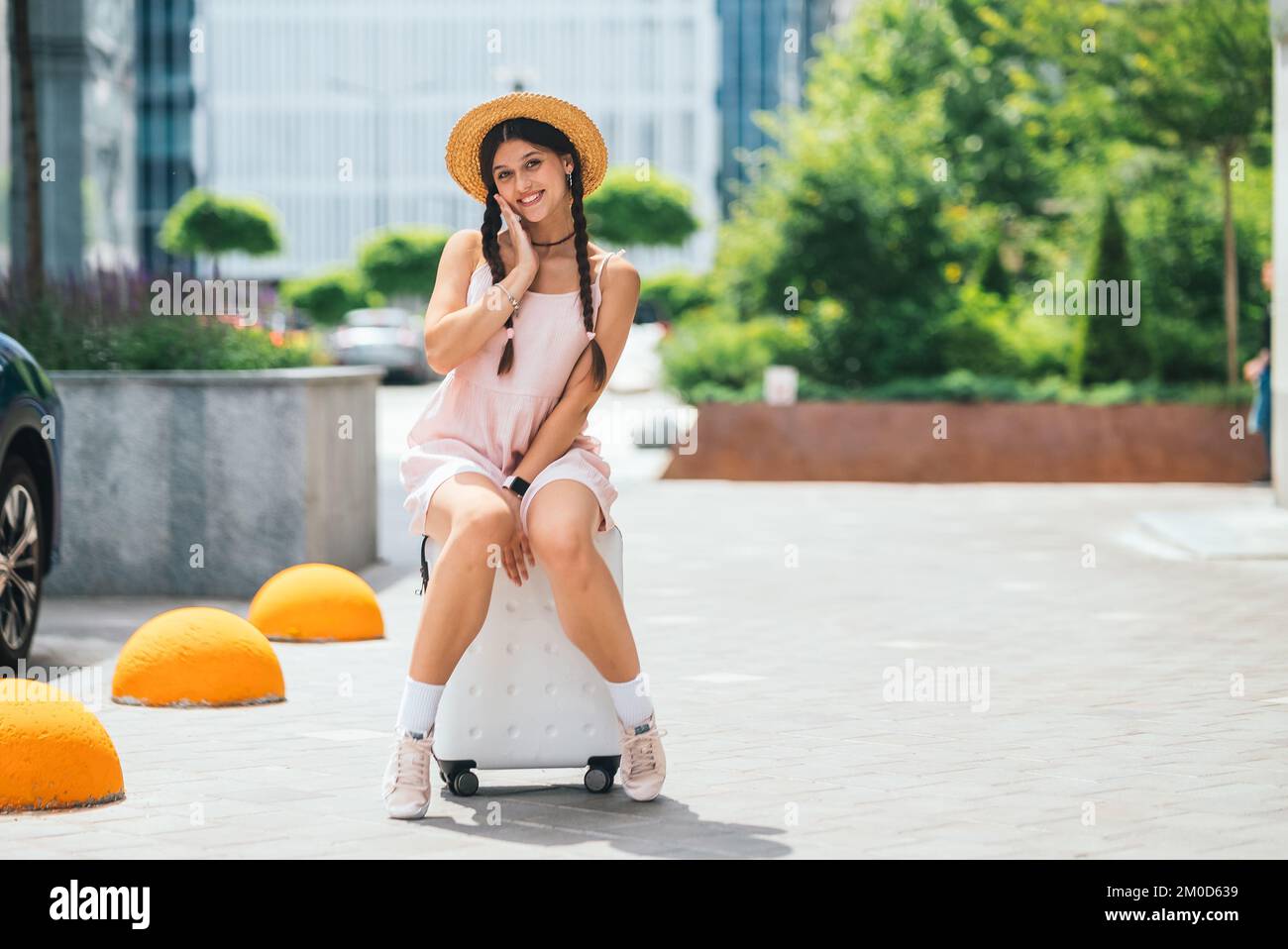 Young beautiful caucasian woman is sitting on suitecase Stock Photo - Alamy