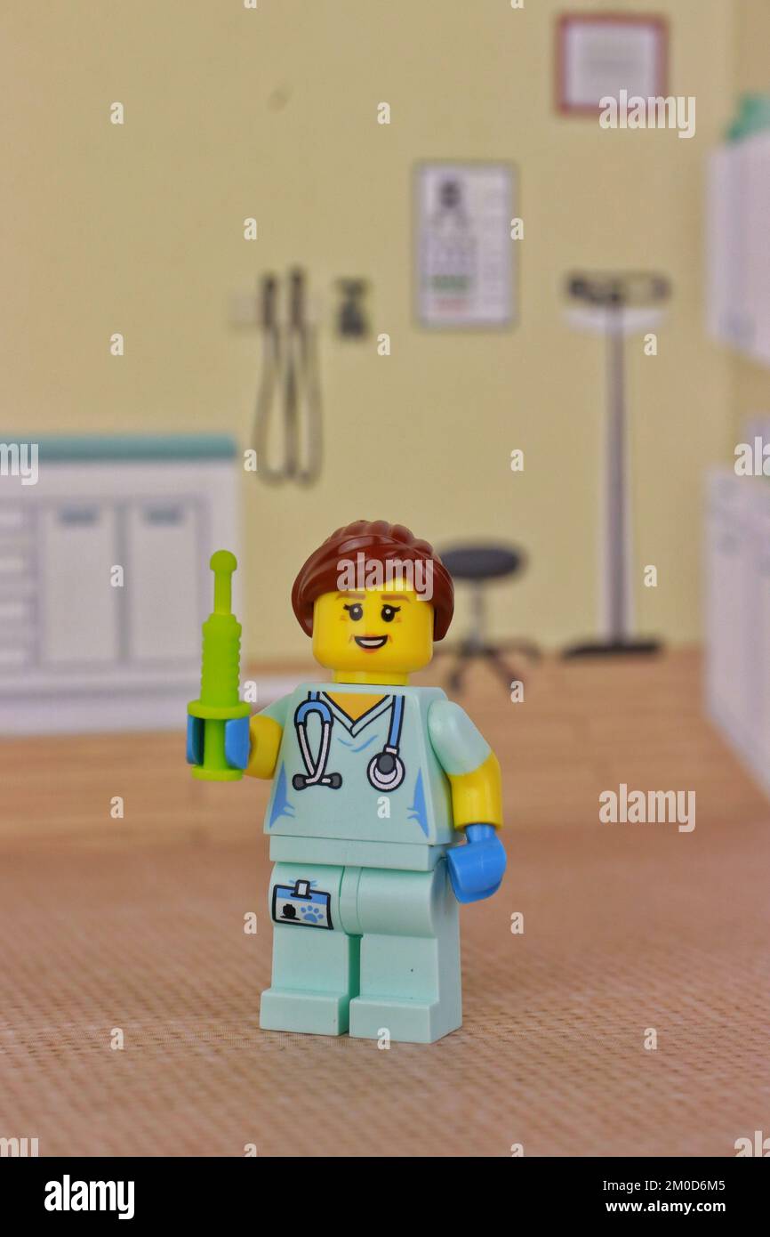 A vertical shot of a female nurse toy, holding a syringe with a needle ...
