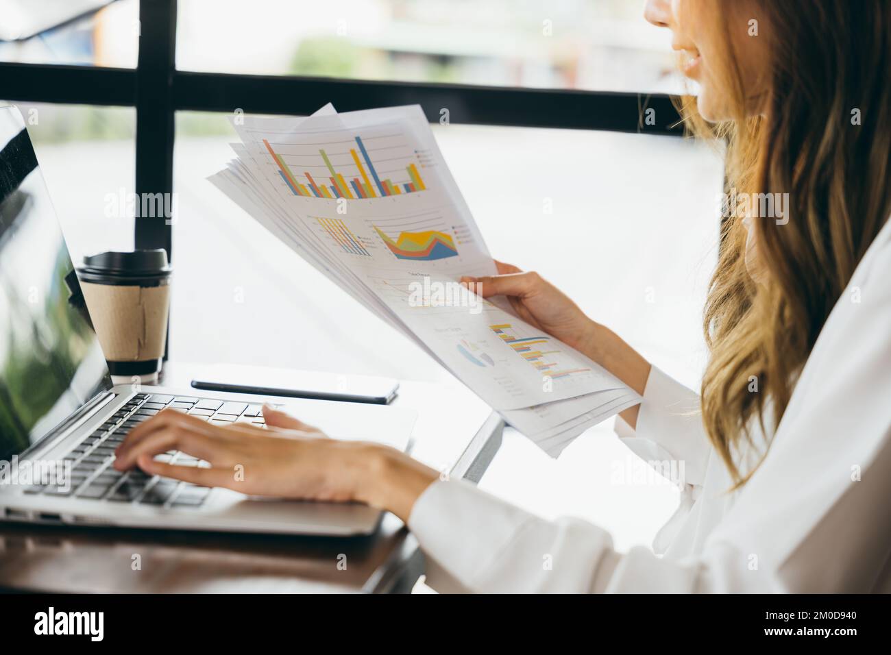 Freelance female hold paperwork documents paper graphs and using laptop ...