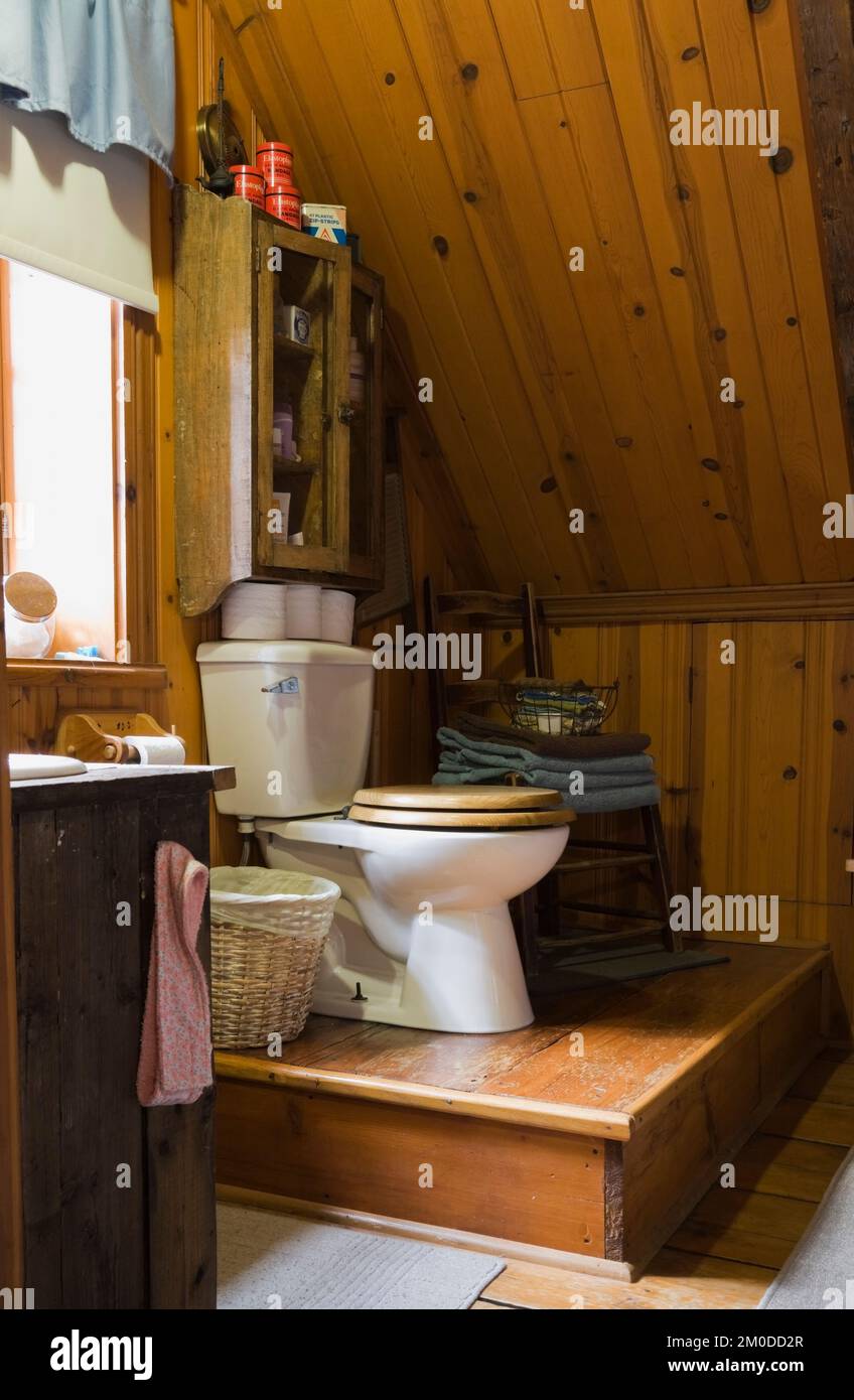 Toilet with wooden seat and lid mounted on elevated wooden platform in ...