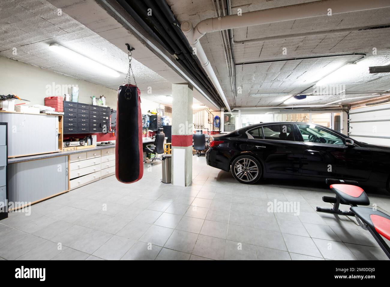 A detached house garage with gray floors, a punching bag and a parked ...