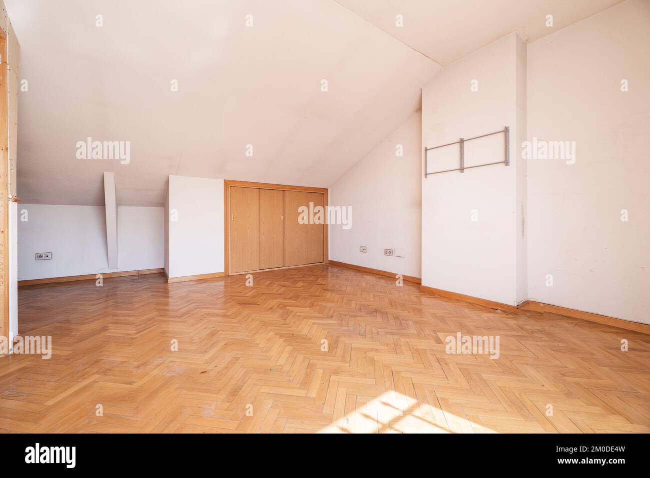 Empty living room with sloping ceilings and wardrobes with wooden ...