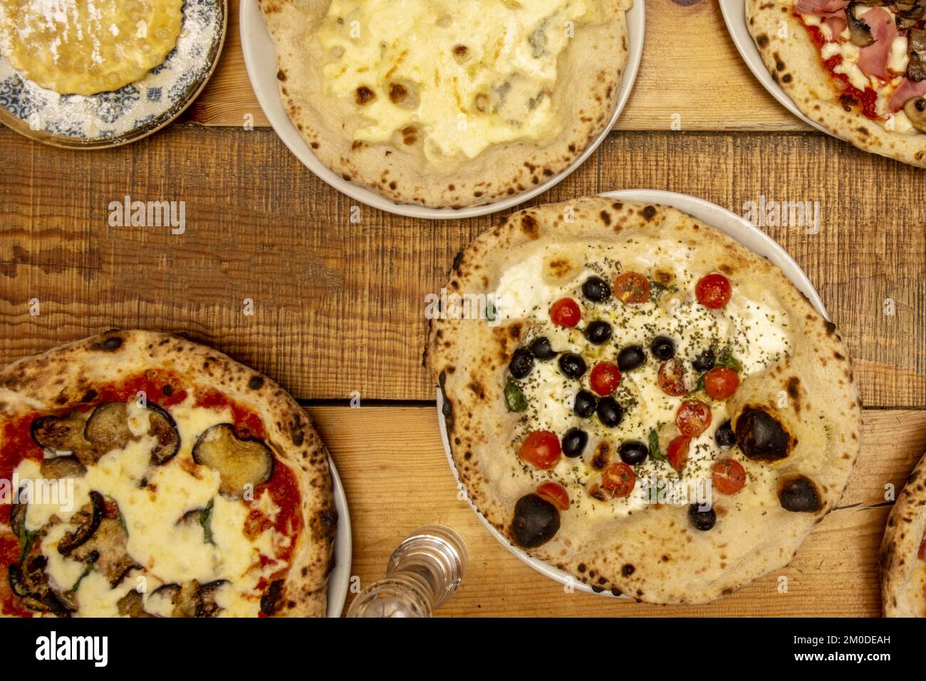 Set of Italian thin crust pizzas with black olives, cherry tomatoes ...