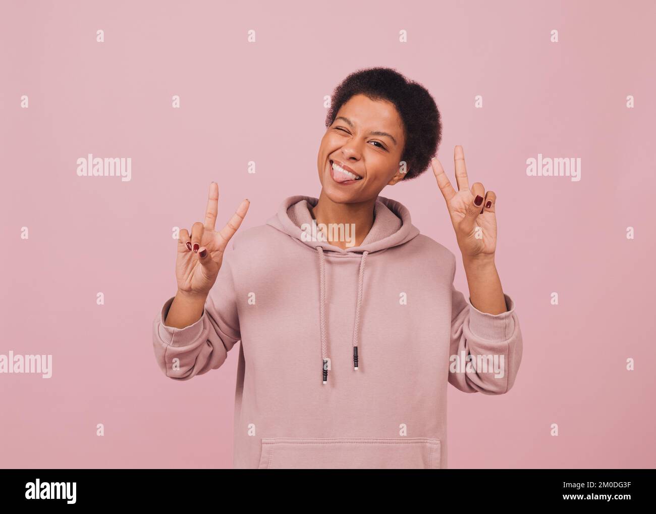 Pretty punk girl in casual wear showing tongue out. Young black woman ...