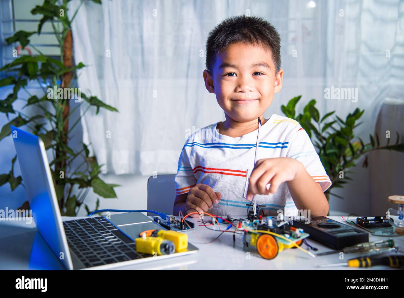 Asian kid boy plugging energy and signal cable to sensor chip with ...