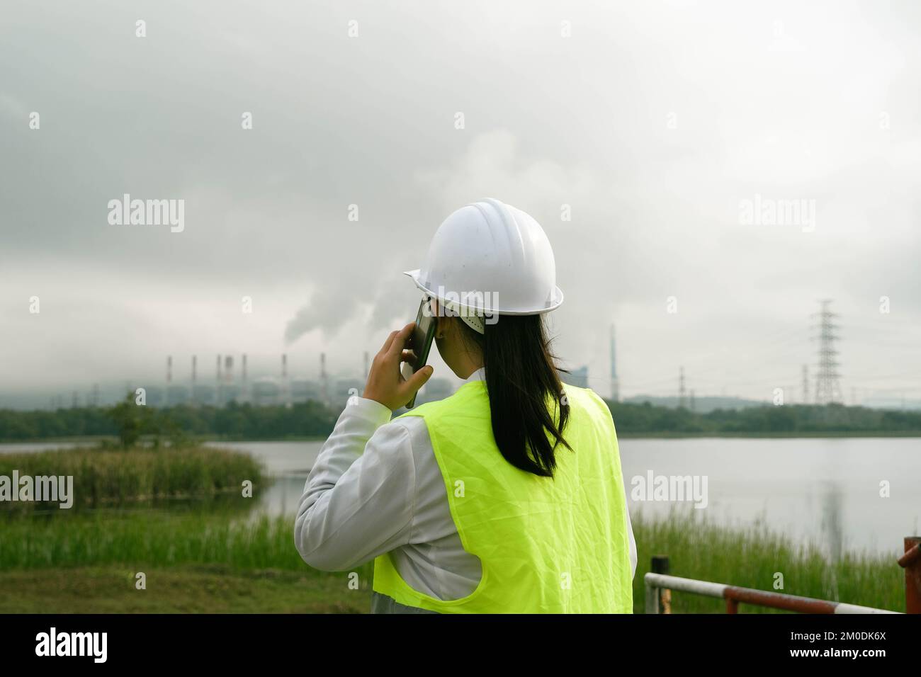 Female chief engineer in green vest and helmet talking on the phone ...