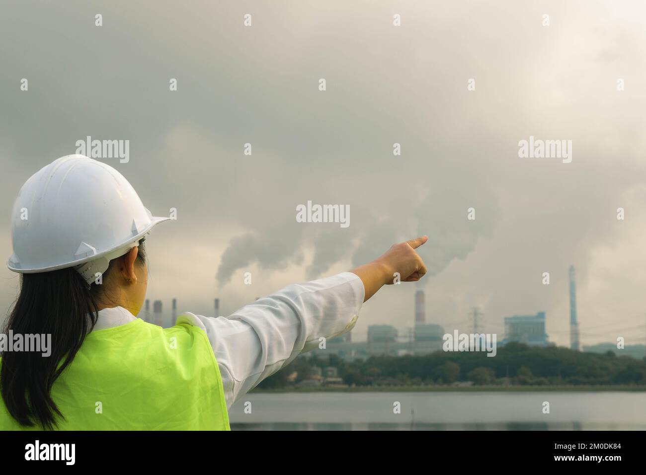 Female chief engineer wearing a green vest and helmet stands outside ...