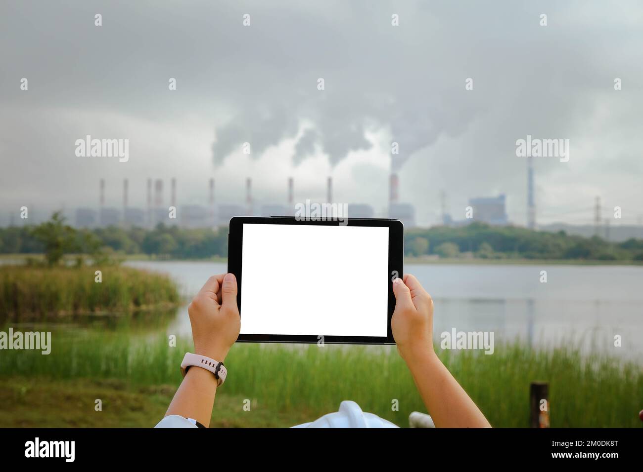 Female chief engineer wearing a green vest and helmet stands outside ...