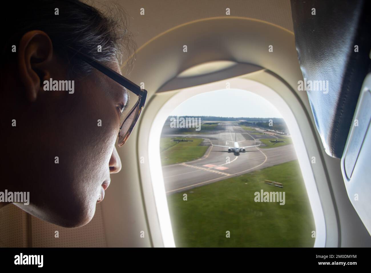 A young woman looks at the airport runway from a flying plane Stock ...