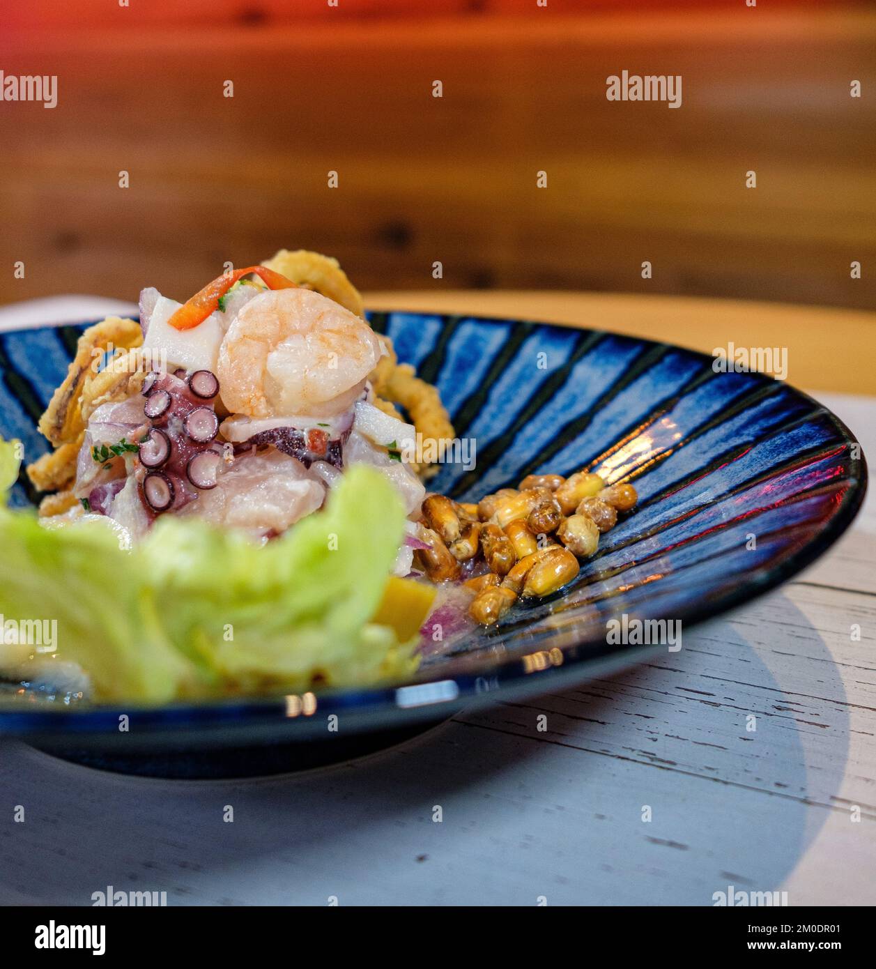 Peruvian ceviche served on a blue plate, accompanied by toasted corn ...