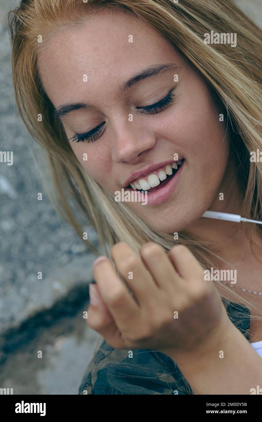 Close-up portrait detail of vain, self-conscious blonde girl as she ...