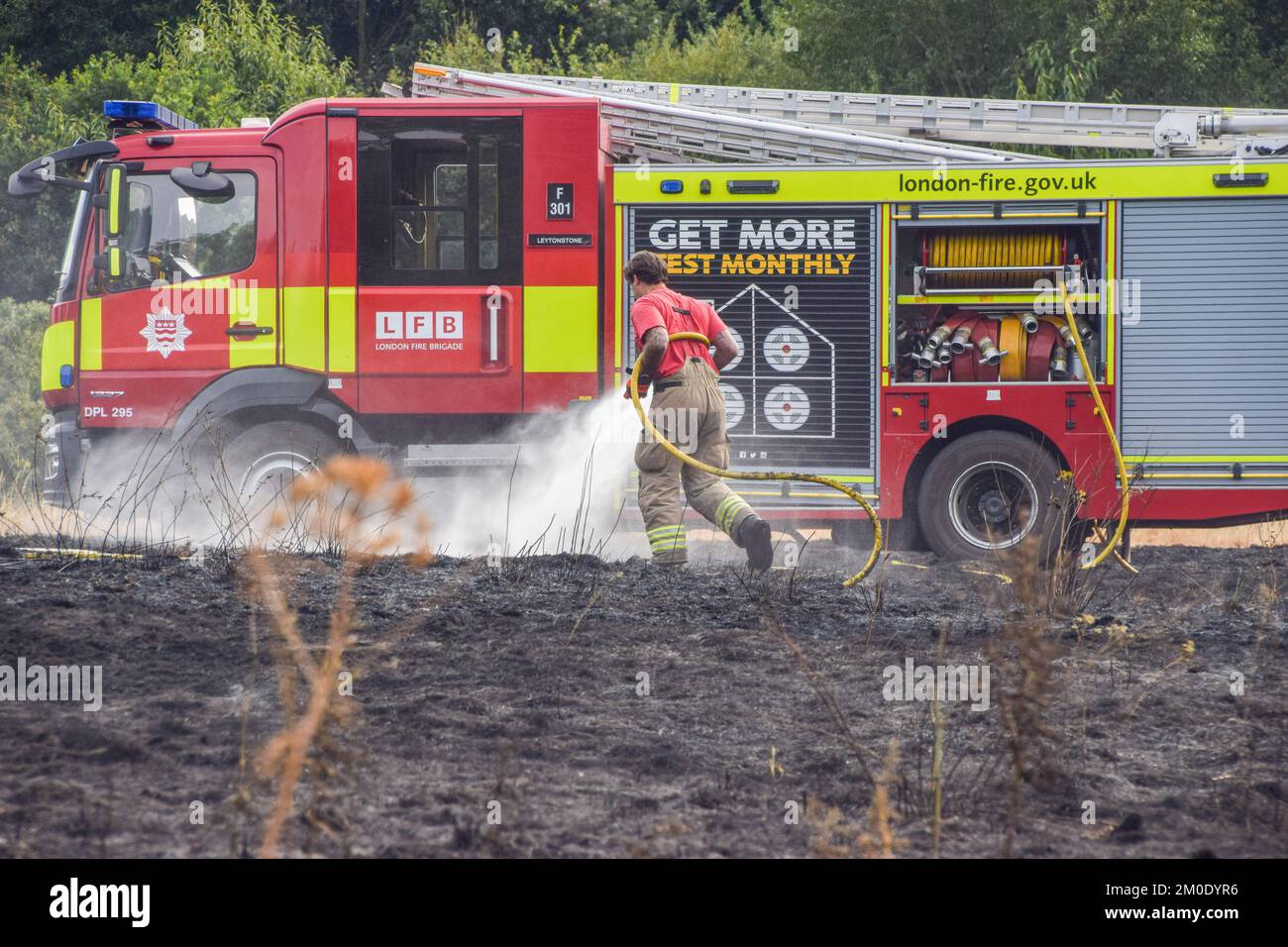 A London Fire Brigade firefighter extinguishes a grass fire in a field ...