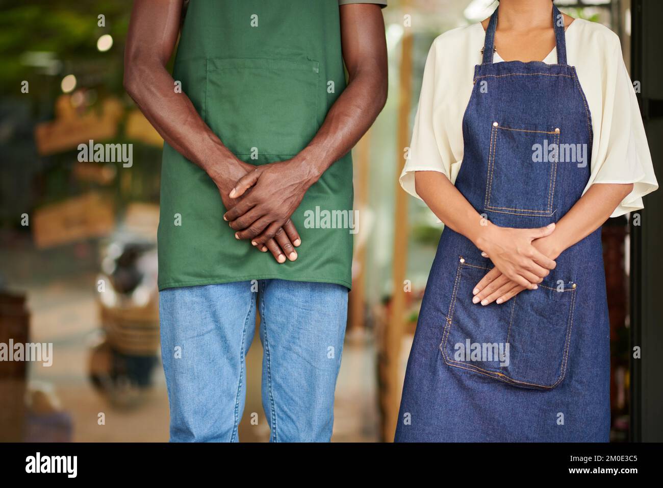 Cropped image of grocery store workers in aprons standing at entrance ...