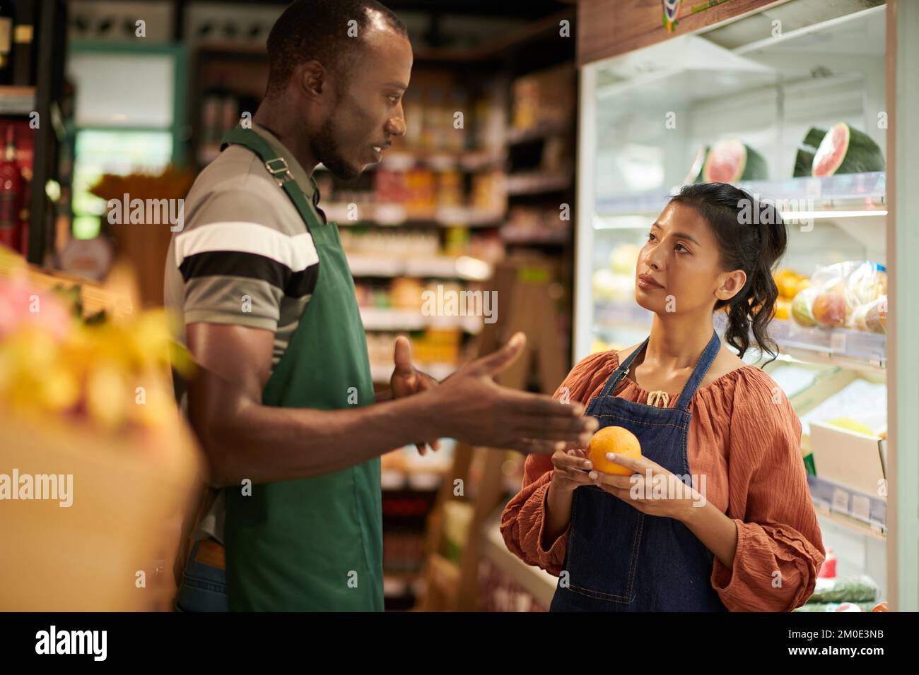 Supermarket manager explaining new employee where to put fresh fruits ...