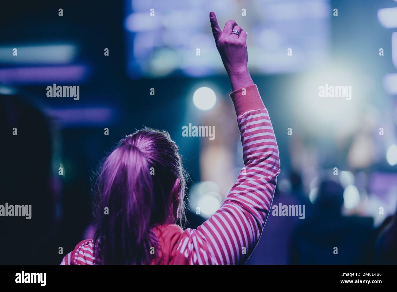 A group of people in church worship with blue and purple light effects ...