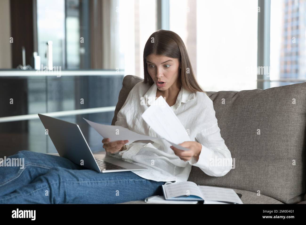 Shocked concerned young freelance employee reading paper notification ...