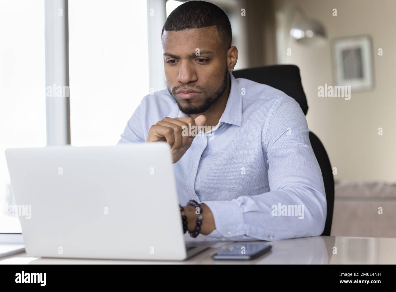 Serious young African business man using Internet app on laptop Stock ...