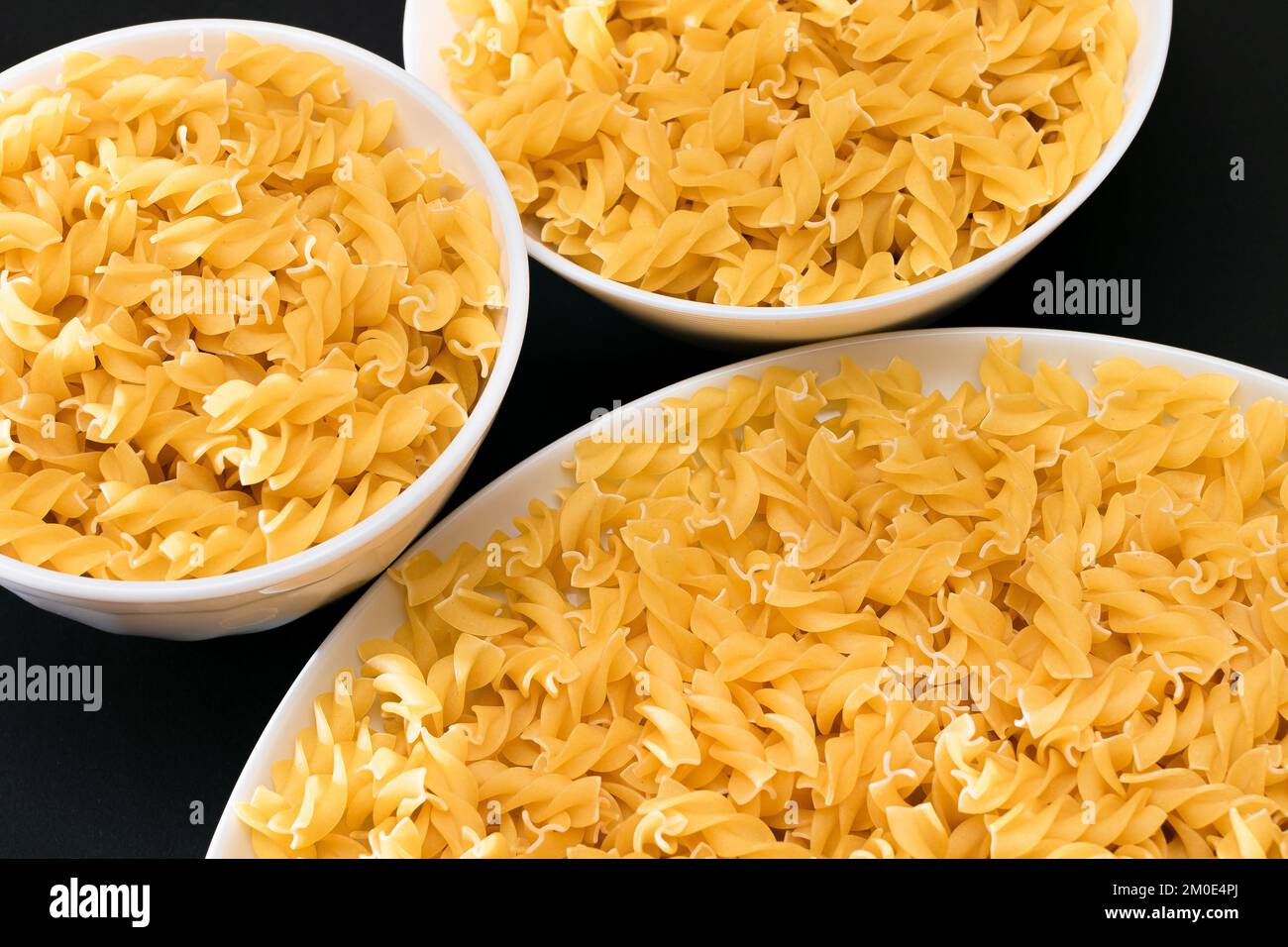 Uncooked Fusilli Pasta Lying on White Plate on Black Background. Raw ...