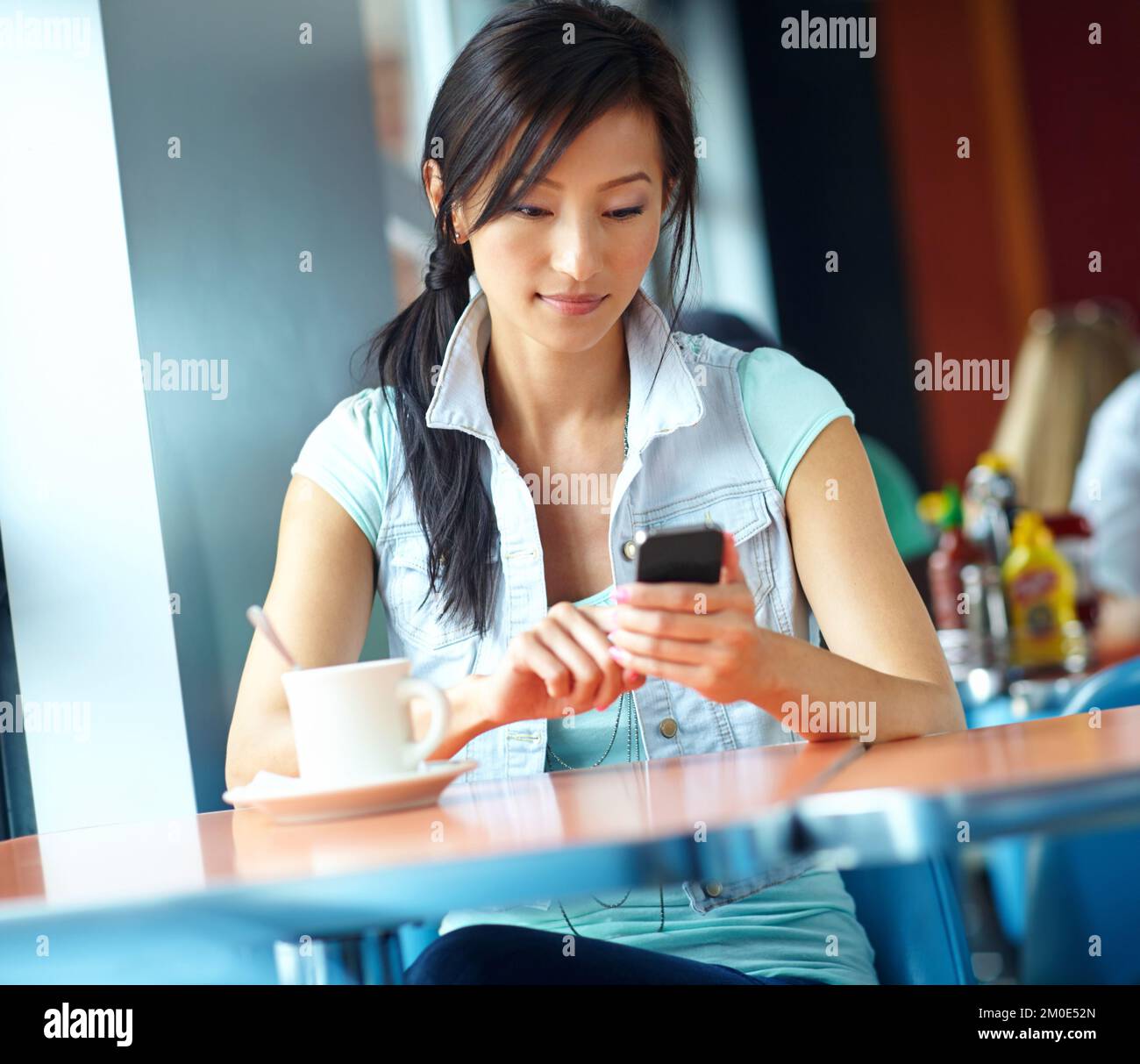 Where are you. A pretty asian woman reading a text message while ...