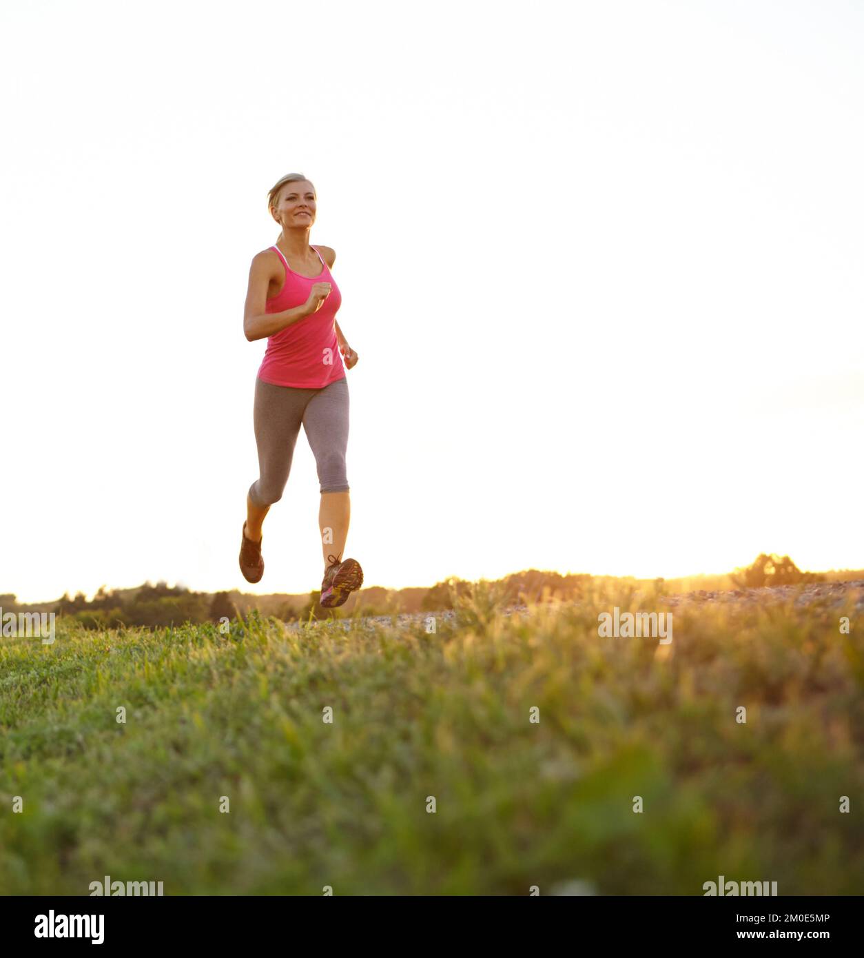 Happiness is running. A beautiful young woman jogging as the sun sets ...