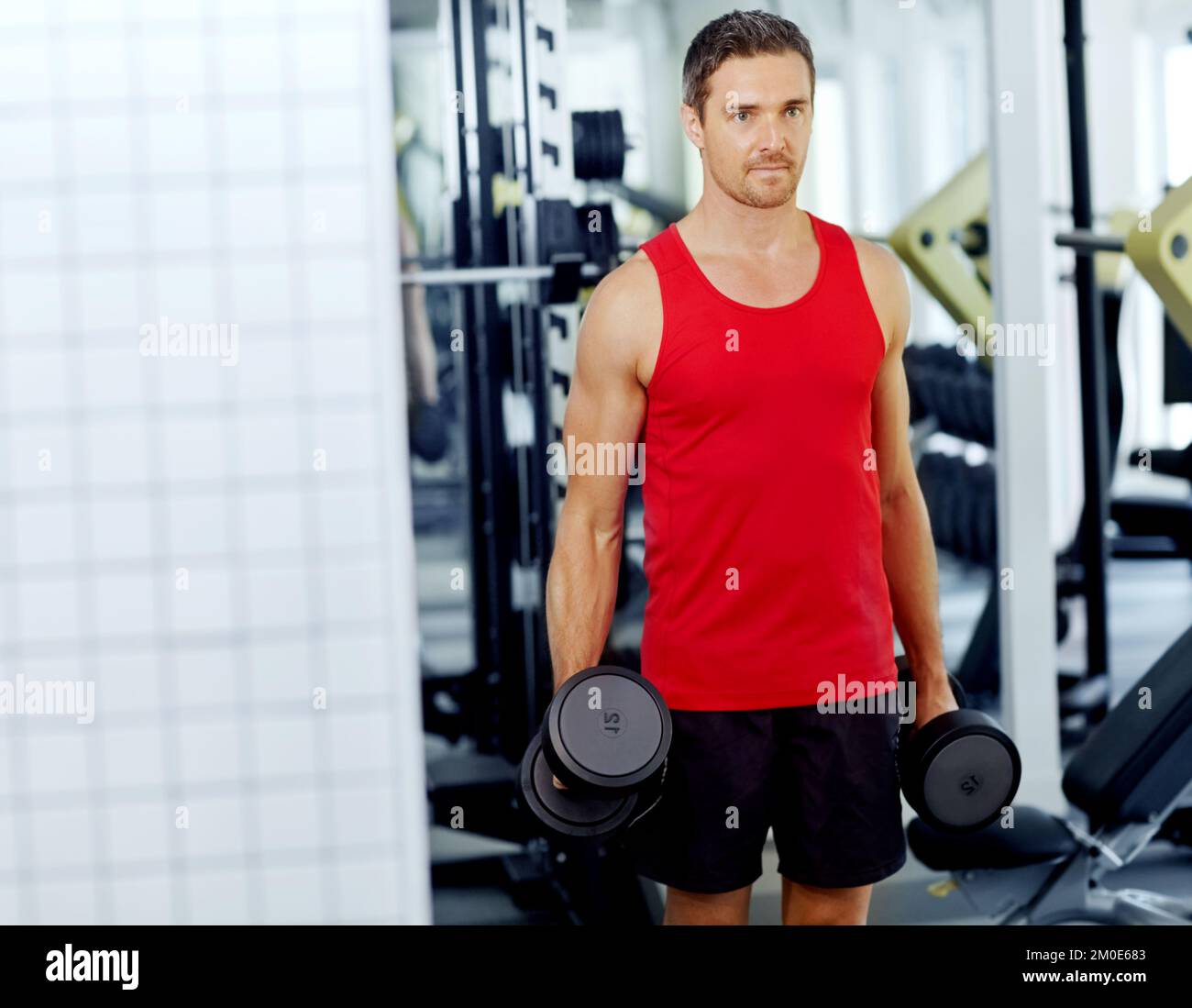 Time to work those pecs. A handsome young man doing weight training at ...