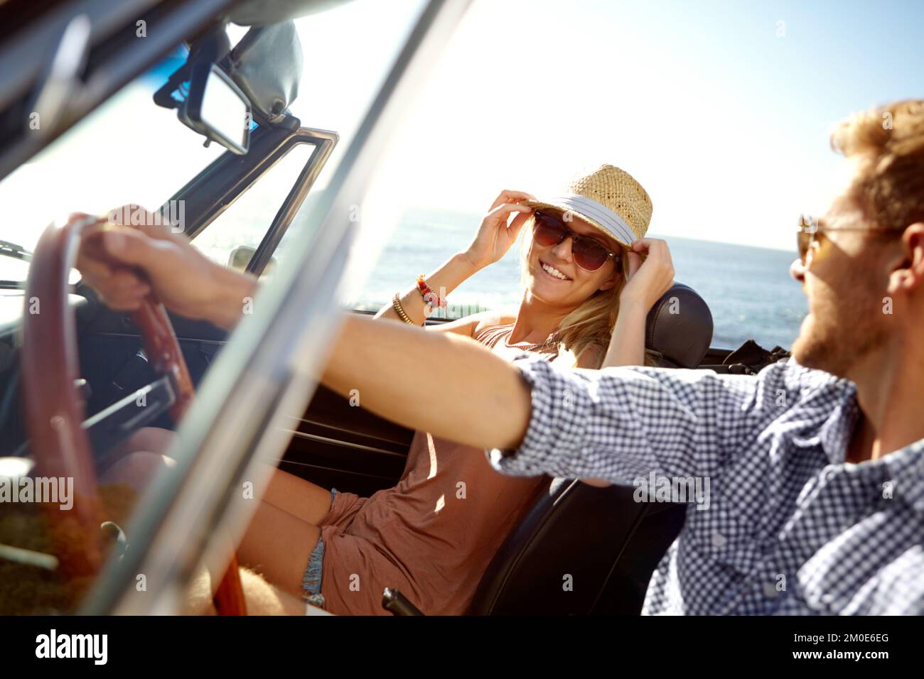 Off on a weekend getaway. A happy young couple driving in a convertible ...