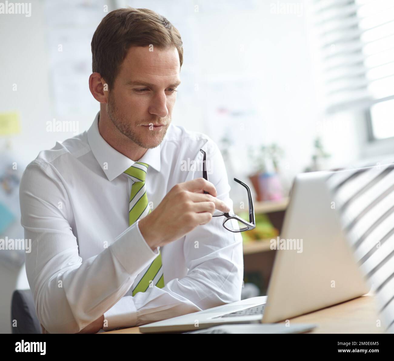 Thinking about the day ahead. A young businessman working on his laptop ...