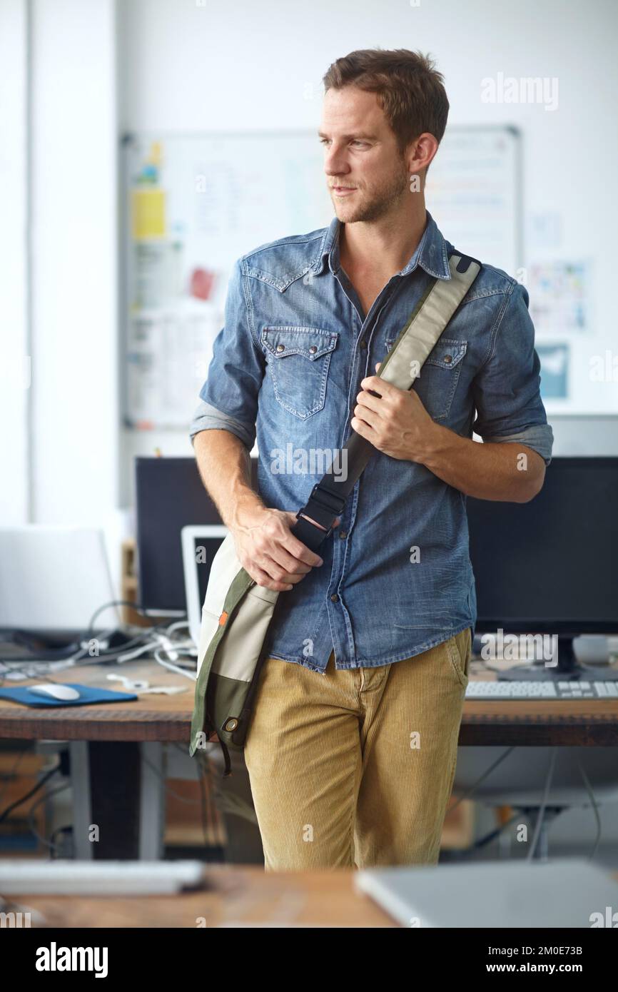 On his way home. A handsome young man with a satchel leaning against a ...