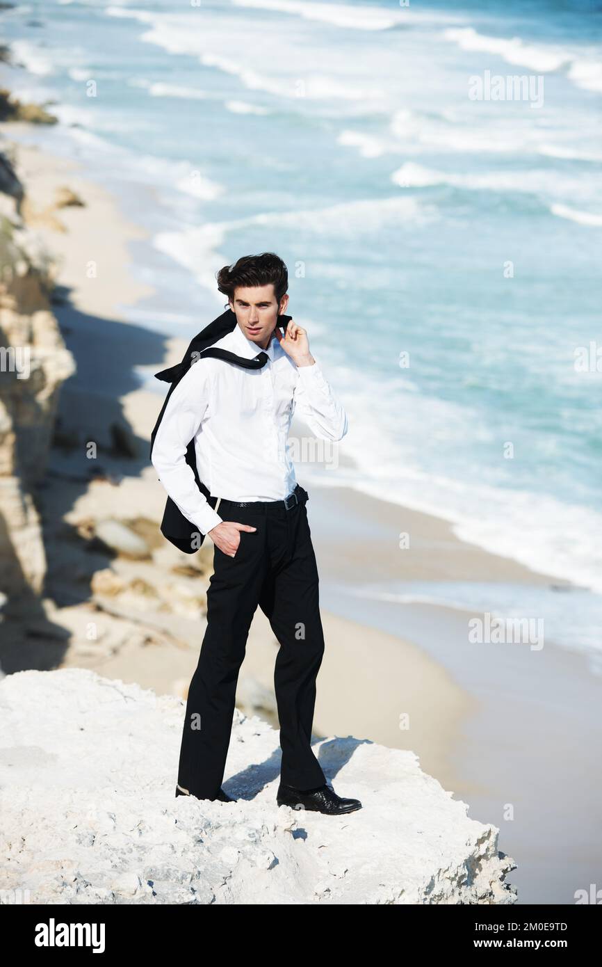 Getting away from the office. Handsome businessman standing on a cliff ...