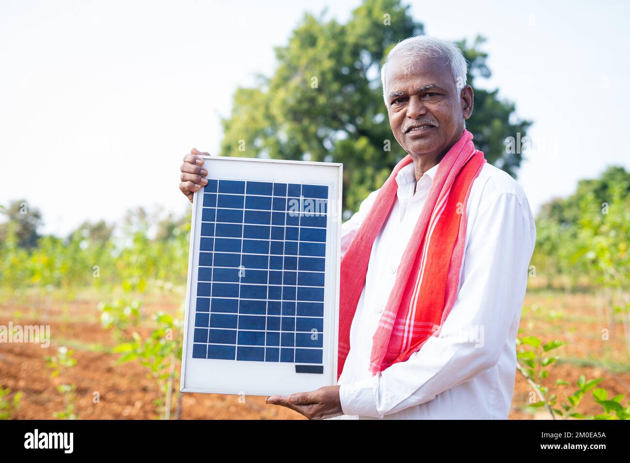 Confident indian farmer showing solar panel by looking at camera ...