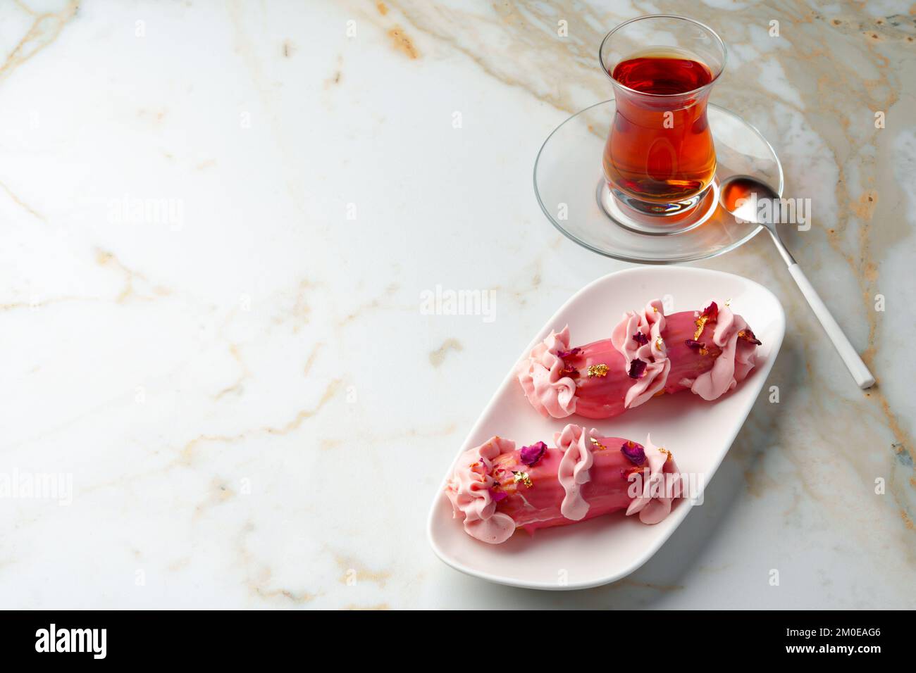 Eclair dessert with pink icing on white table Stock Photo - Alamy